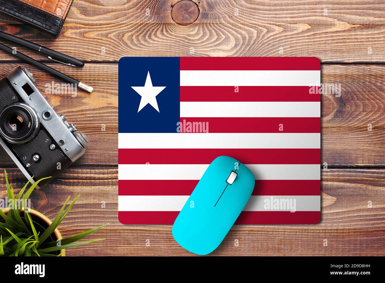 Liberia flag on wooden background with blue wireless mouse on a mouse ...