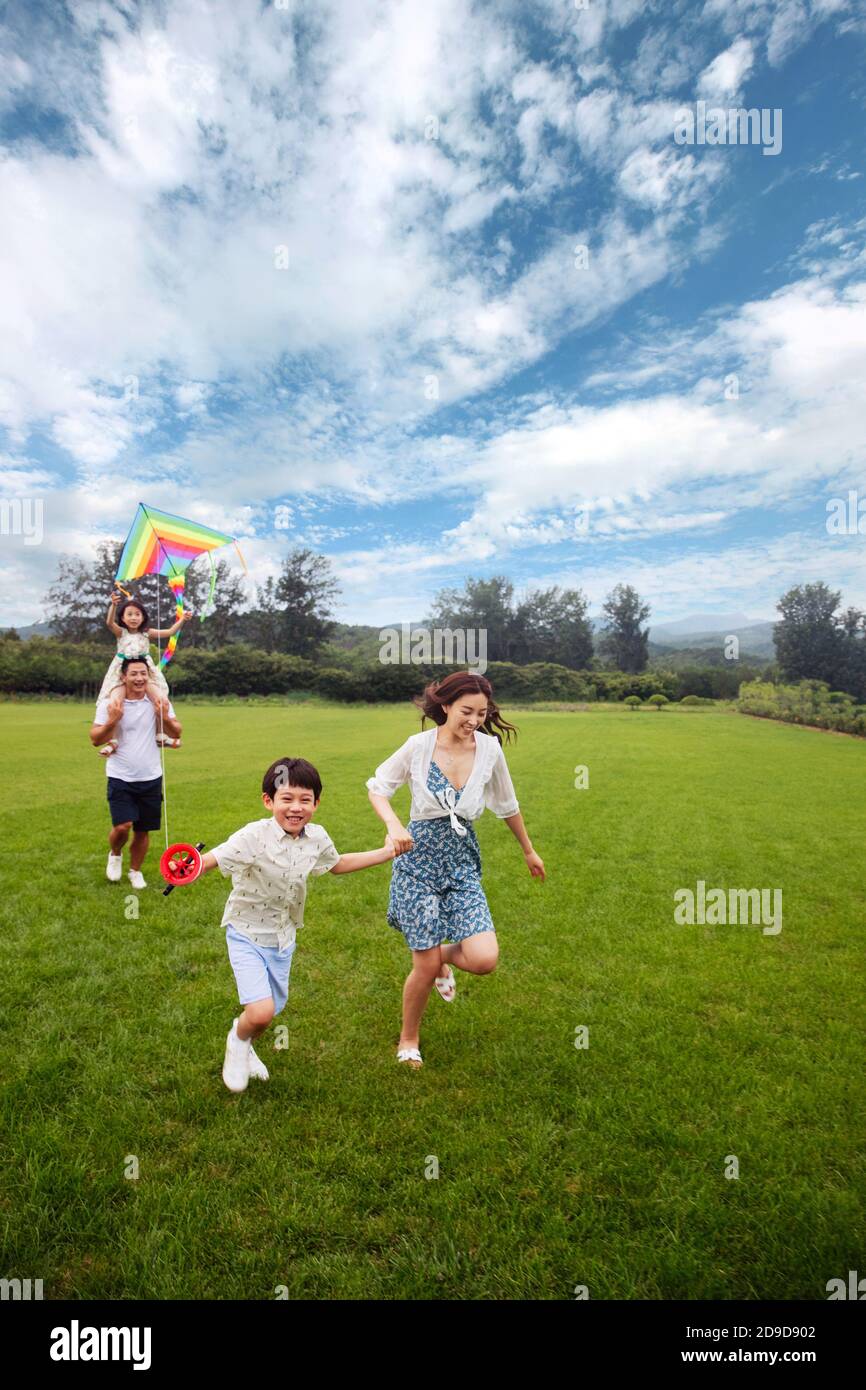 The happy family of four is flying a kite Stock Photo - Alamy