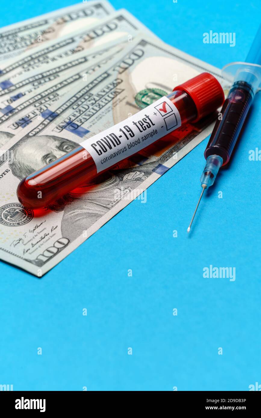 Close up 100 US dollar bills and blood sample in test tube over blue ...