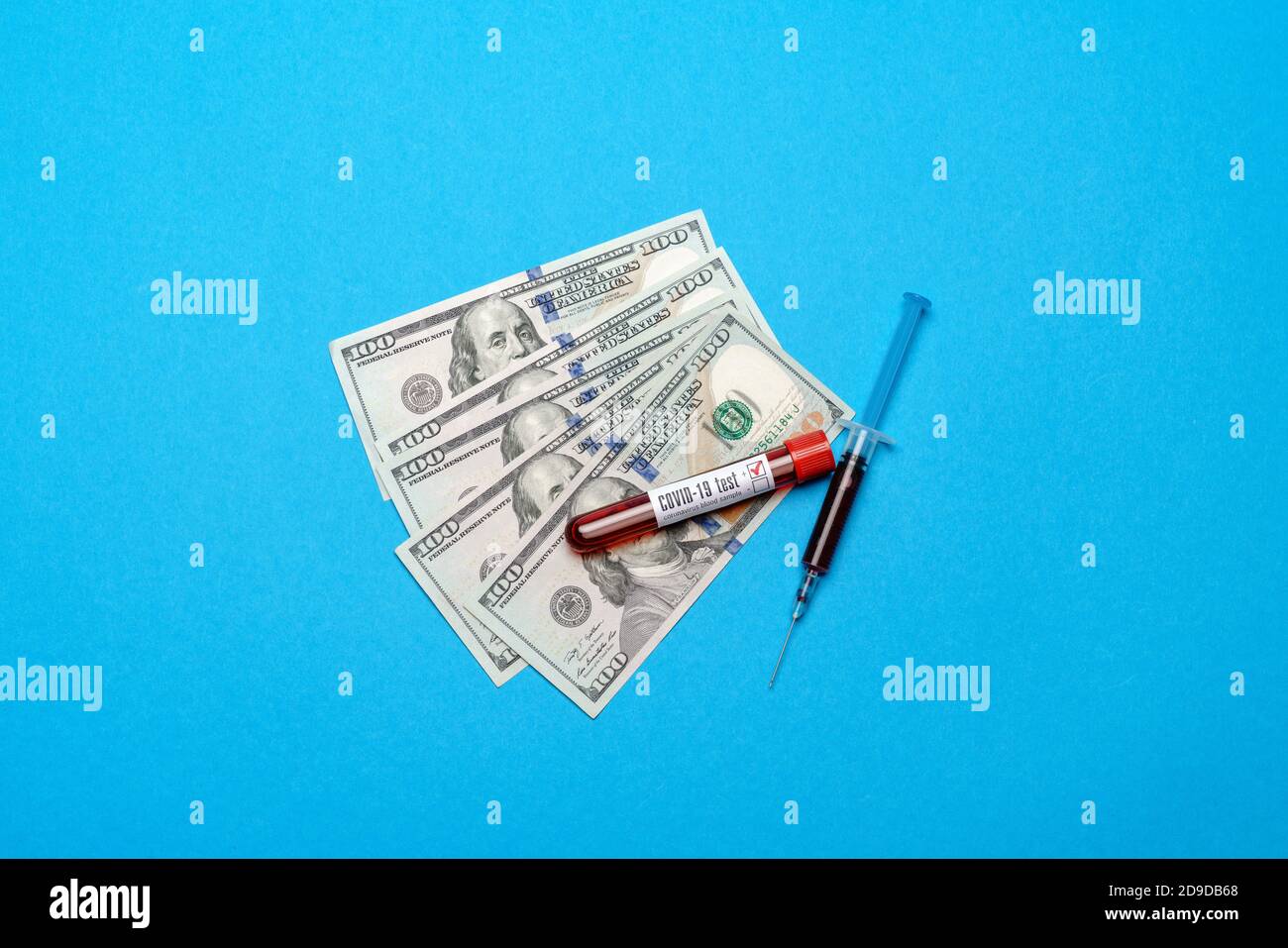 Close up 100 US dollar bills and blood sample in test tube over blue ...
