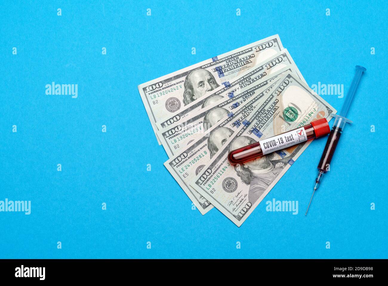 Close up 100 US dollar bills and blood sample in test tube over blue ...