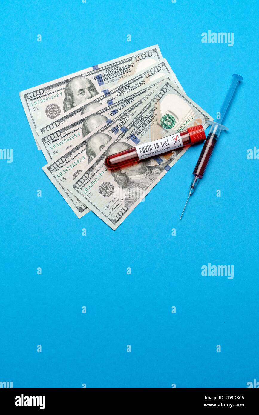 Close up 100 US dollar bills and blood sample in test tube over blue ...