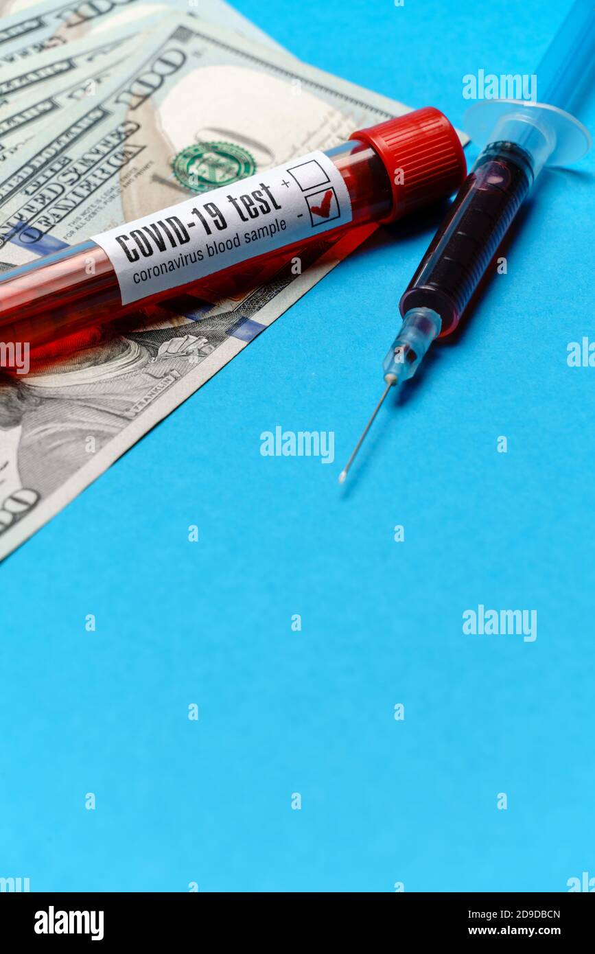 Close up 100 US dollar bills and blood sample in test tube over blue ...