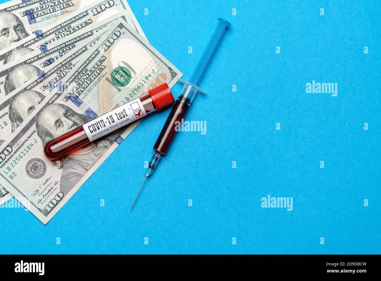 Close up 100 US dollar bills and blood sample in test tube over blue ...