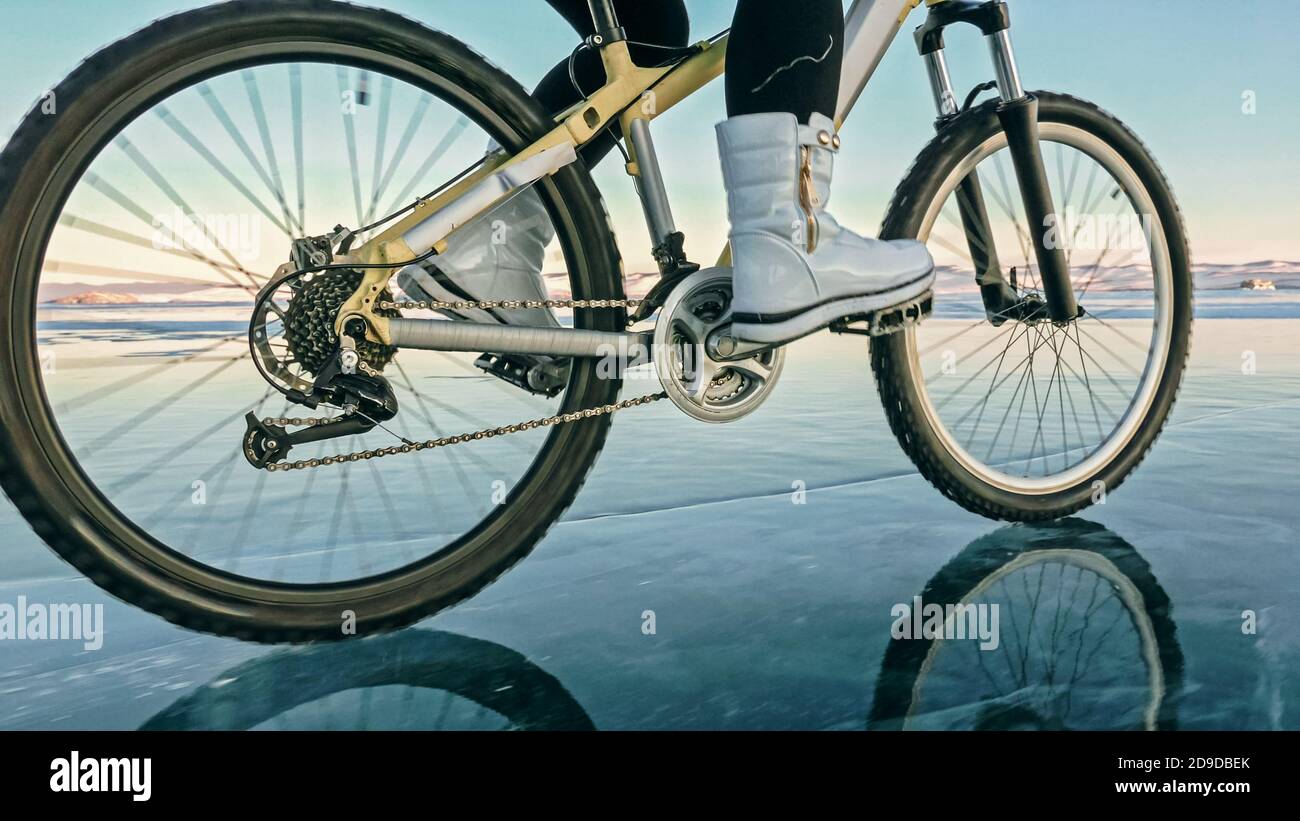 Woman is riding bicycle on the ice. Tires on bike are covered wi Stock ...