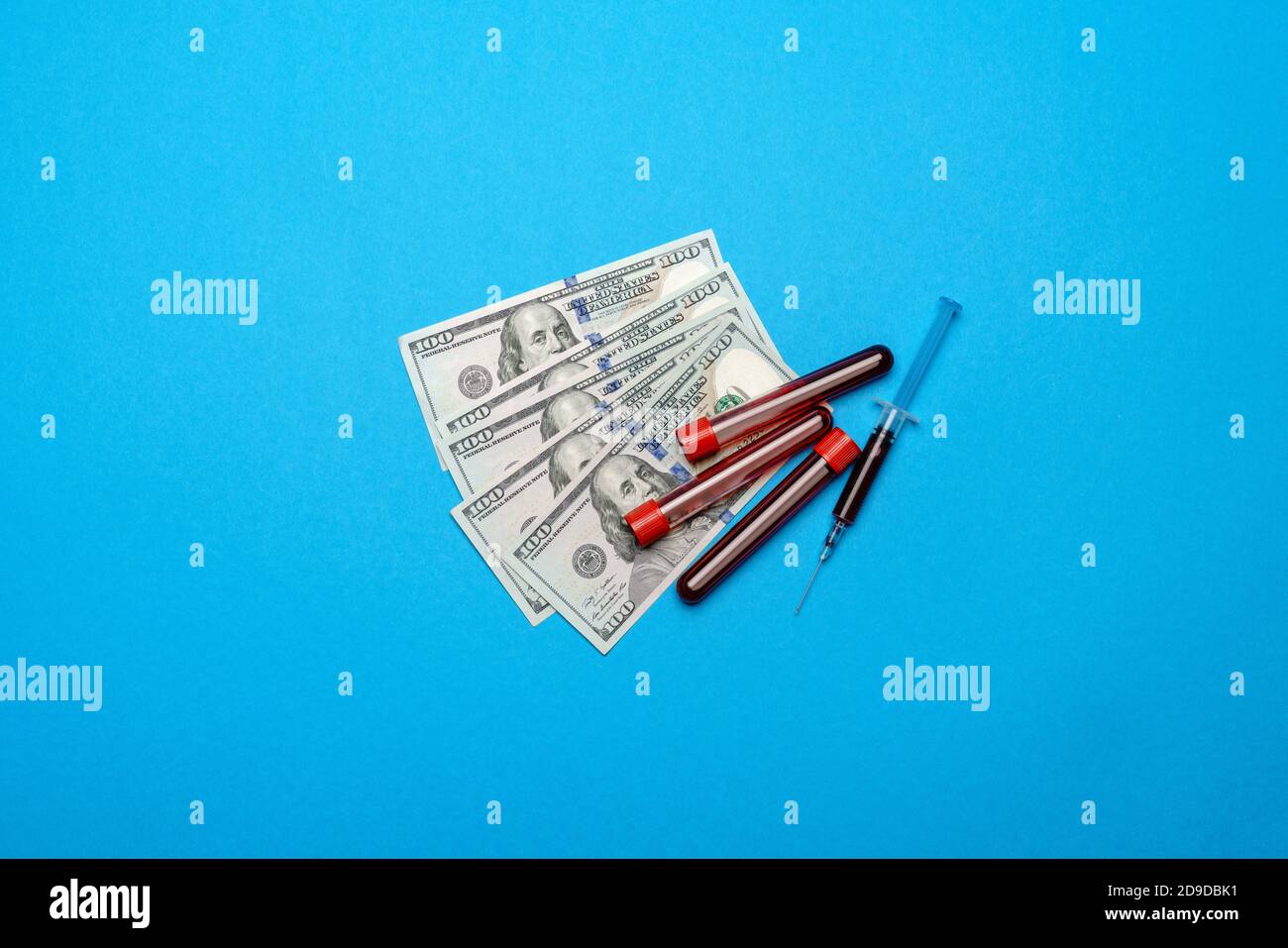 Close up 100 US dollar bills and blood sample in test tube over blue ...