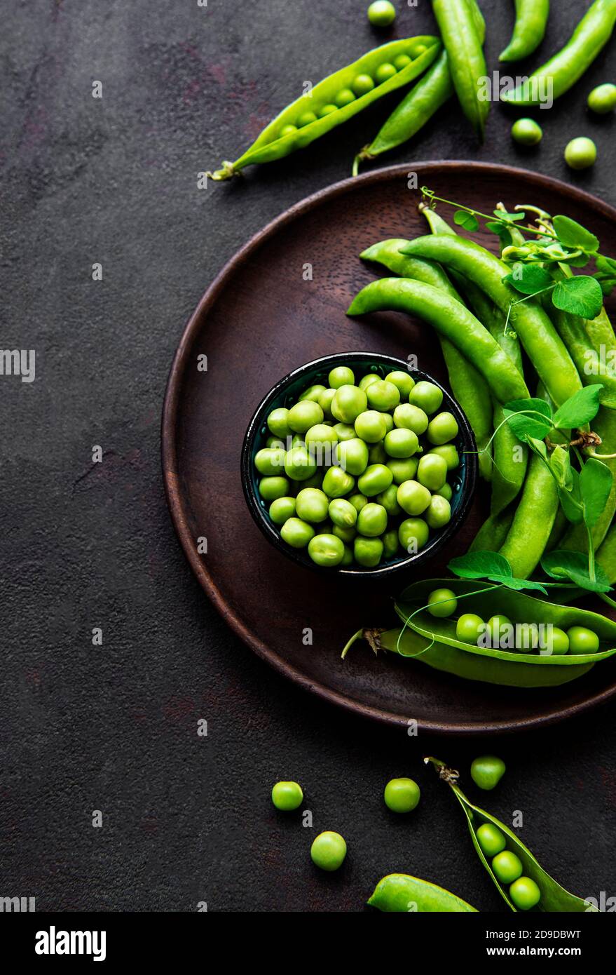 Green peas in bowl with fresh pods on the black concrete background ...