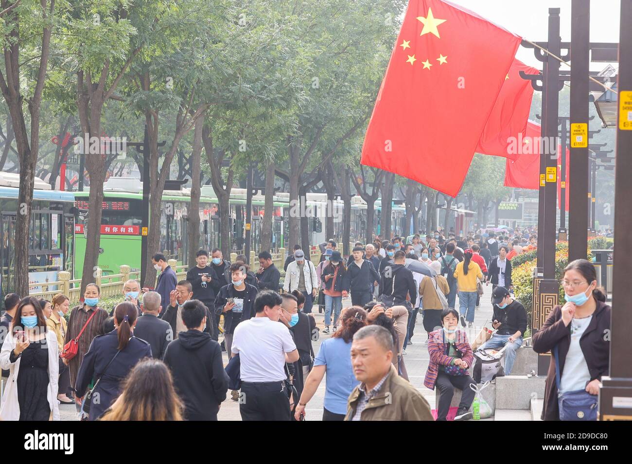 Flock of tourists walk along the street in the city with national flags ...