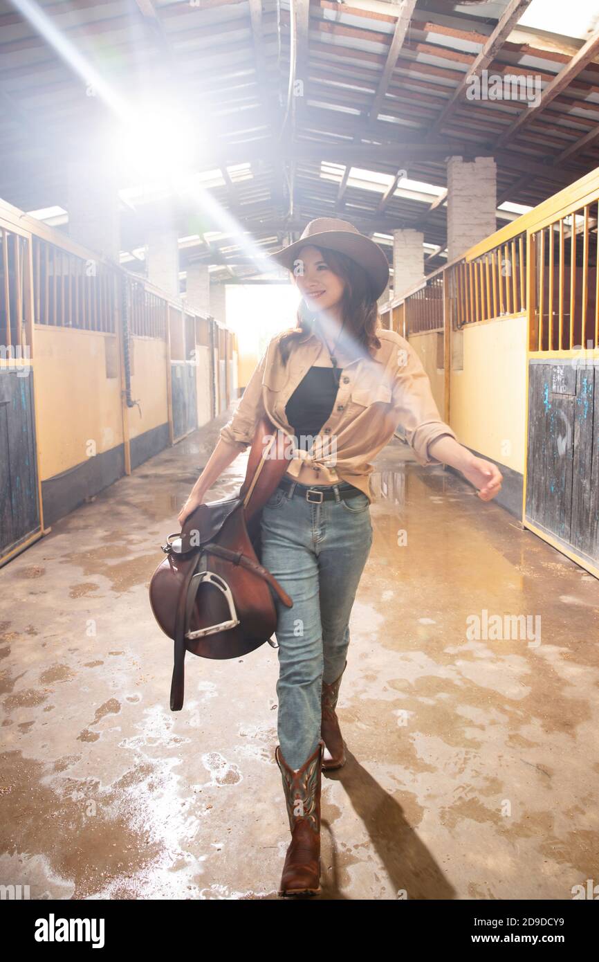The stable holding the saddle of young women walk Stock Photo - Alamy