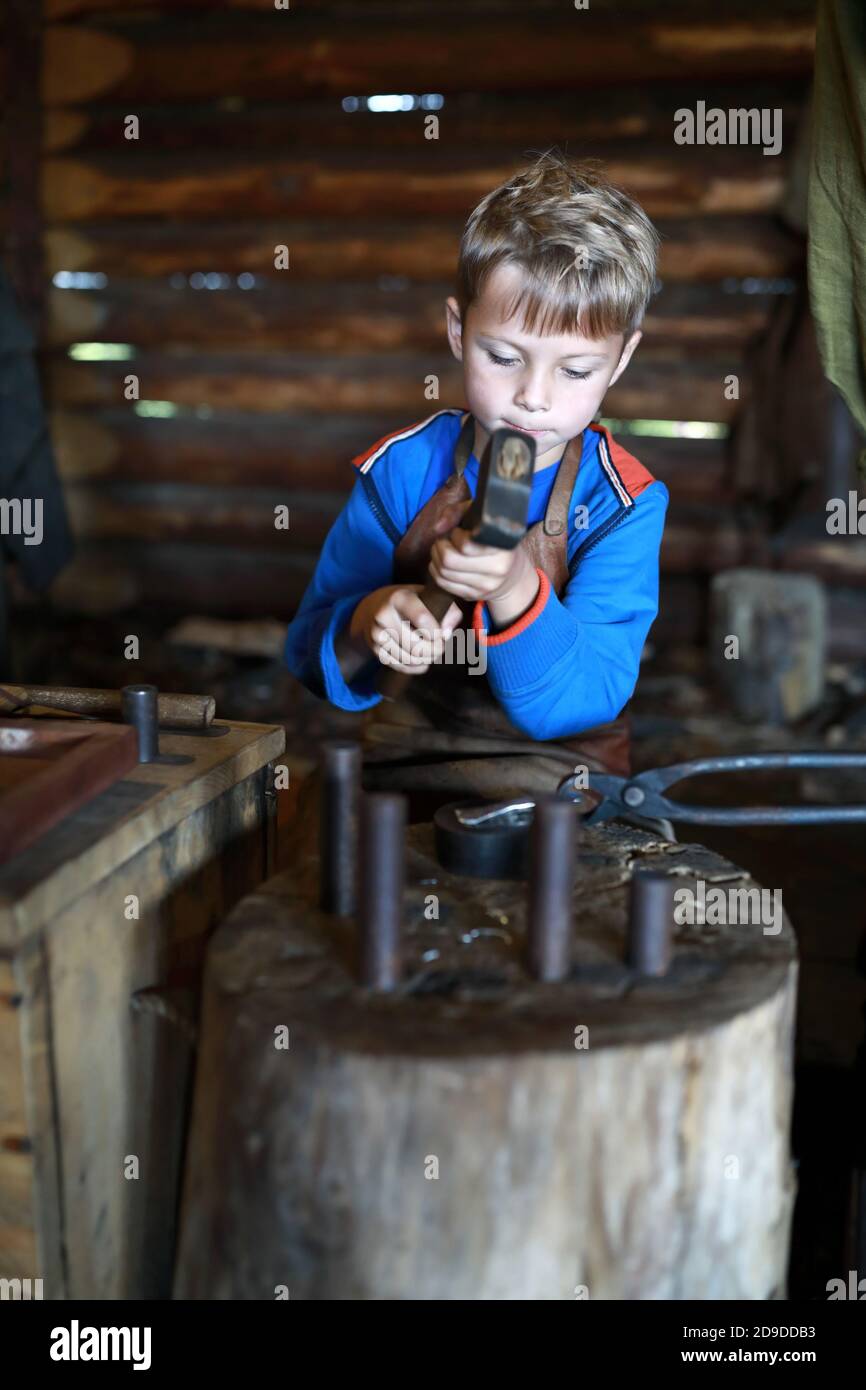 Boy learning to work with hammer in forge Stock Photo - Alamy