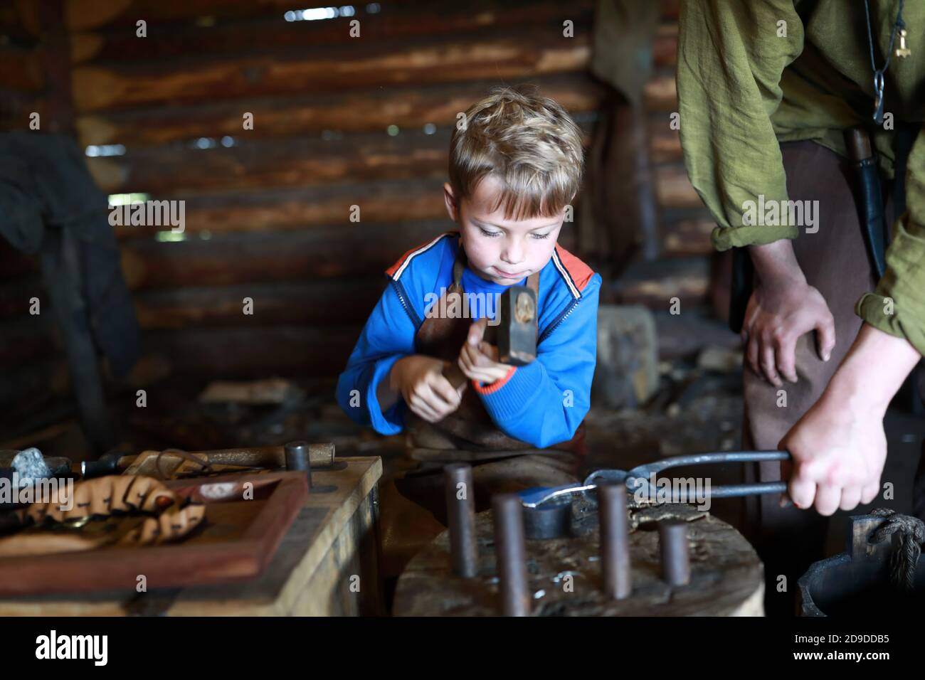 Child learning to work with hammer in forge Stock Photo - Alamy