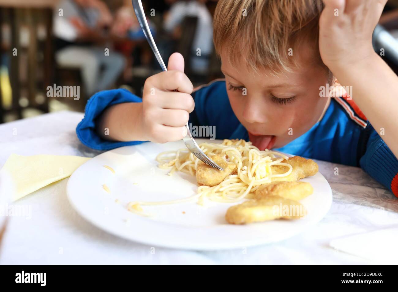 Kid eating spaghetti with nuggets in restaurant Stock Photo - Alamy