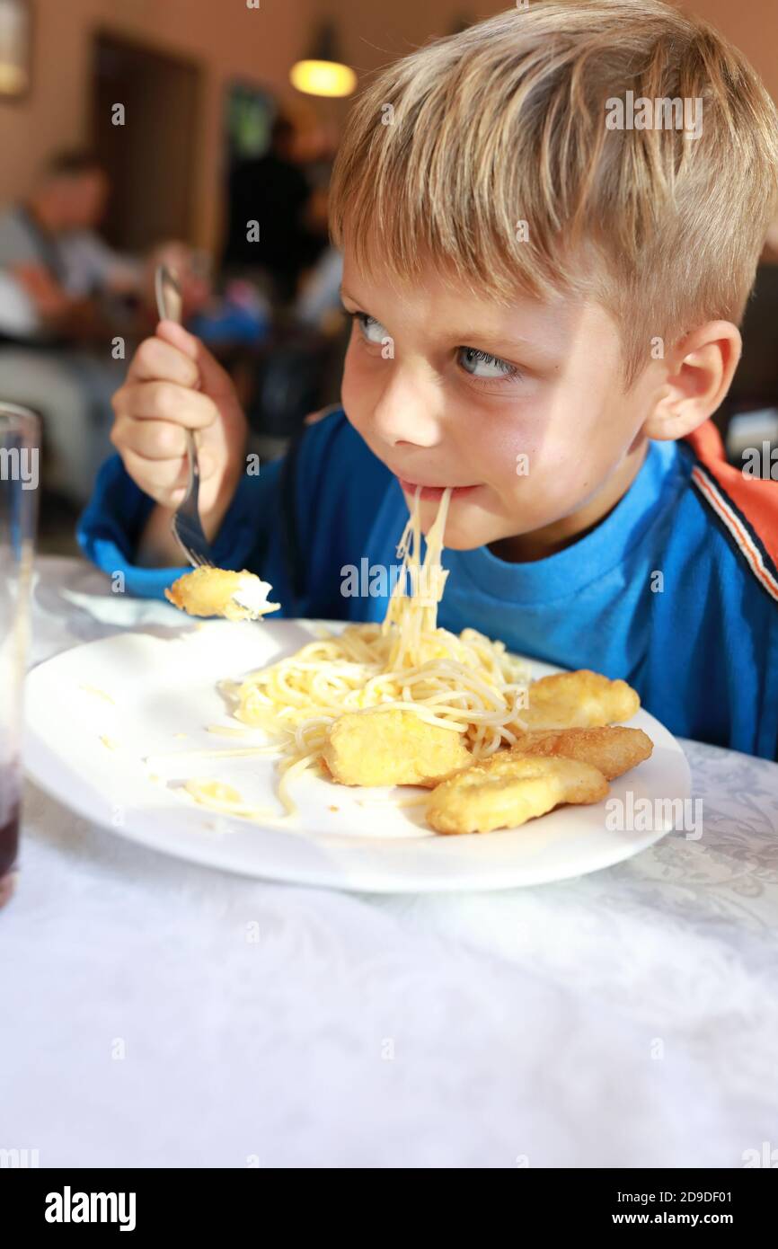 Child eating spaghetti with nuggets in restaurant Stock Photo - Alamy