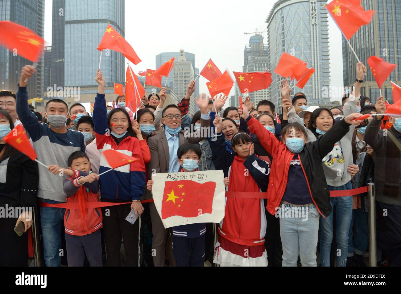 People wave Chinese flags while watching the Chinese flag raising ...
