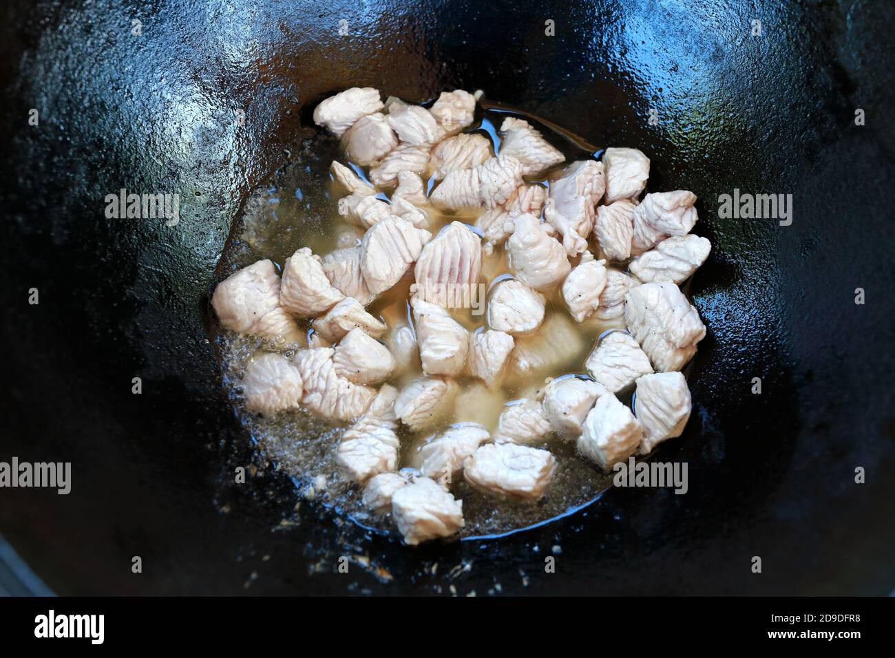 Frying meat in a cauldron for pilaf Stock Photo - Alamy