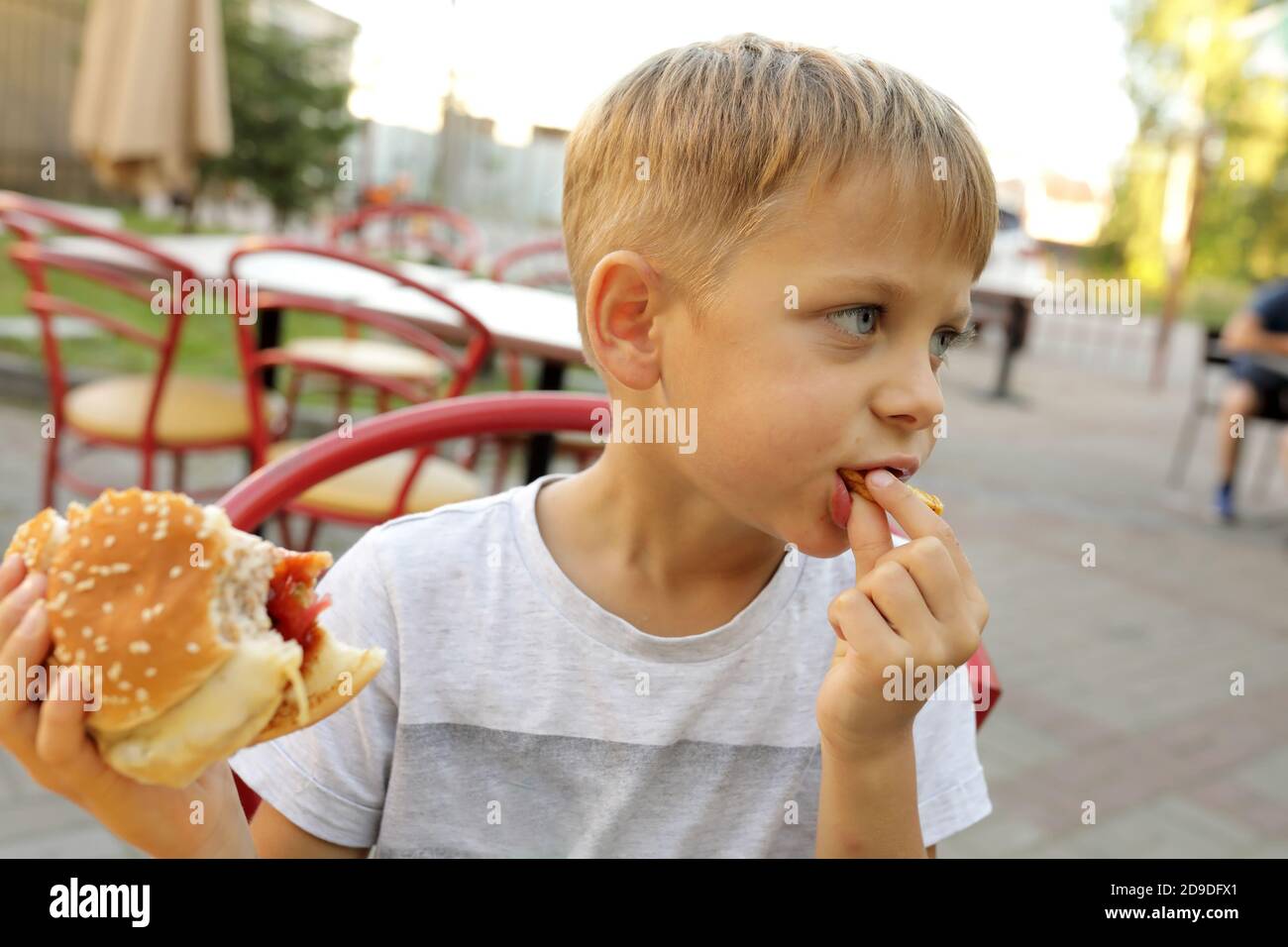 Child eating fries and burger in restaurant Stock Photo - Alamy