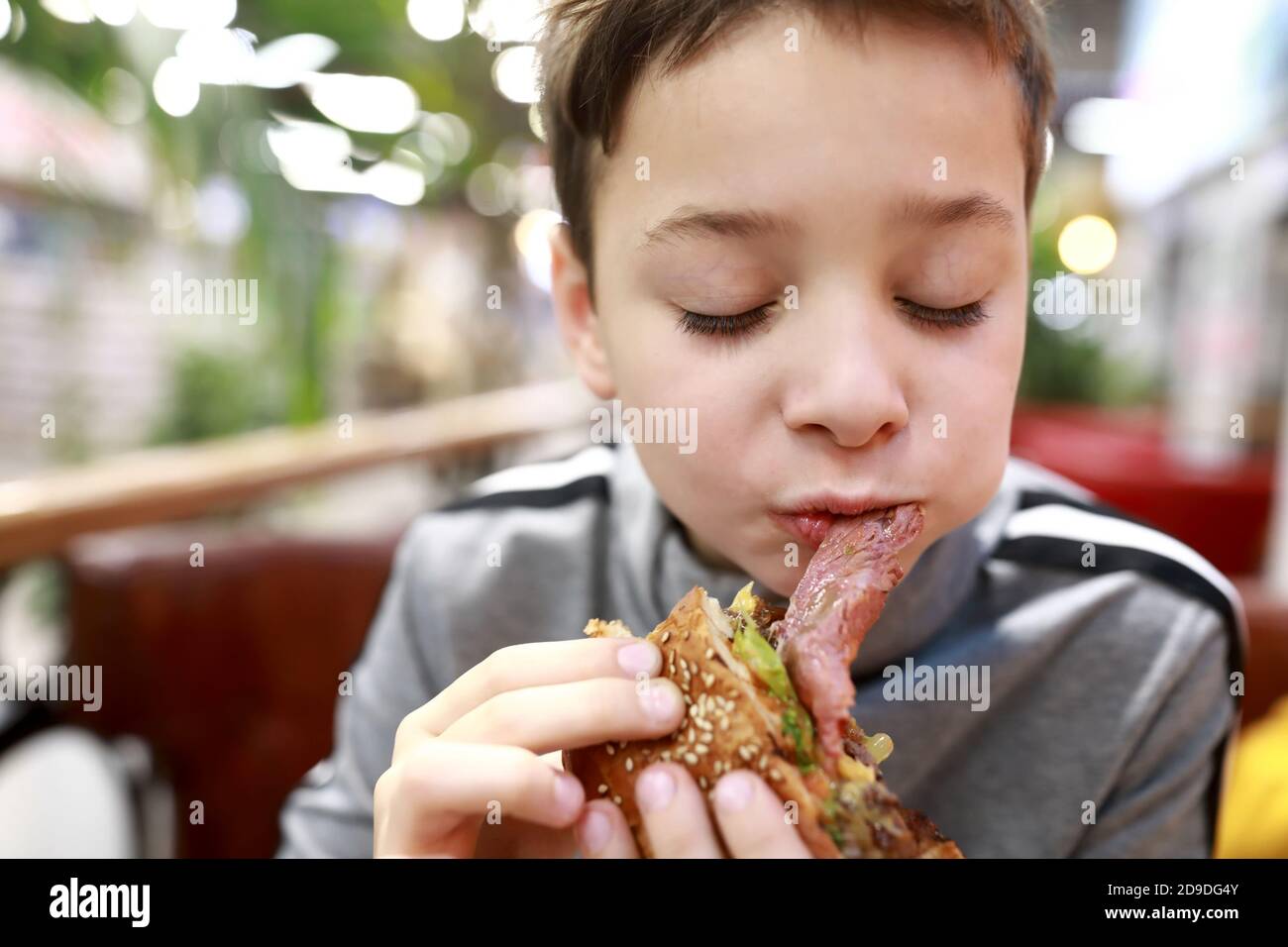 Portrait of child eating burger in restaurant Stock Photo - Alamy