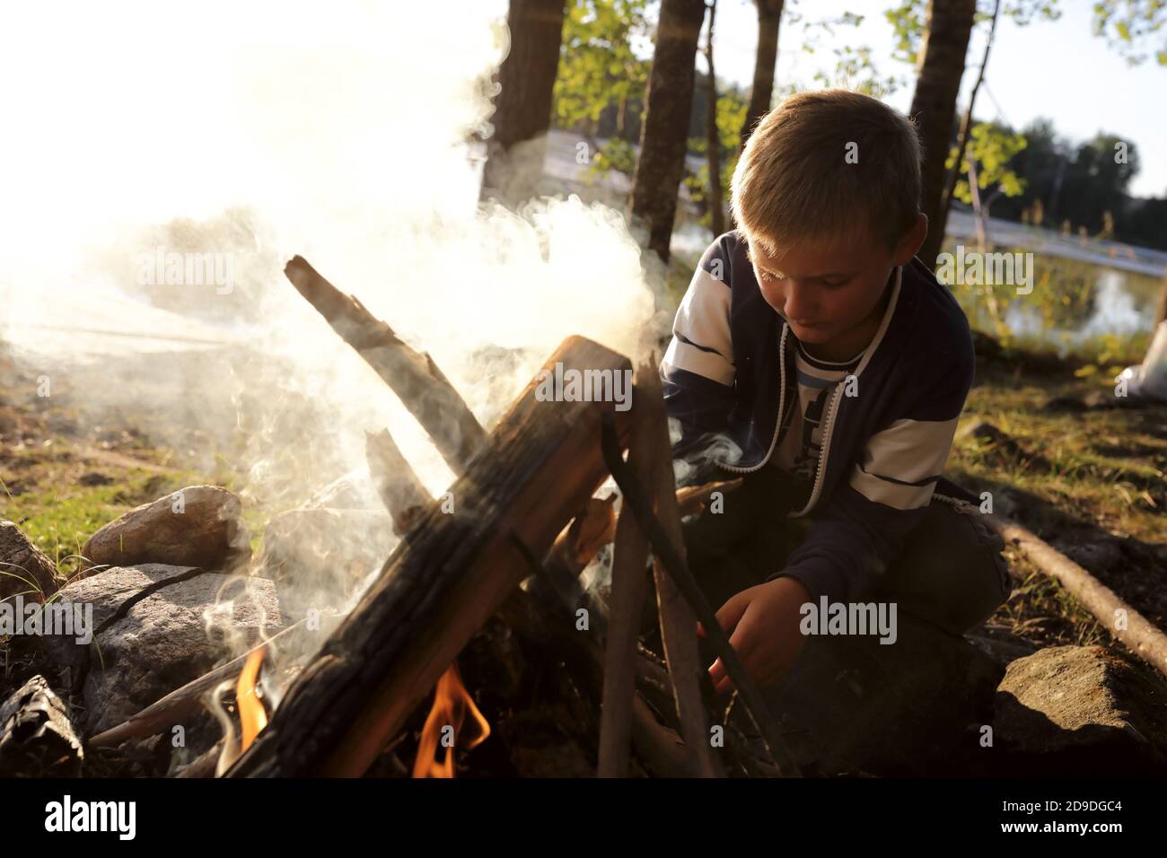 Boy by fire in forest in evening, Karelia Stock Photo - Alamy