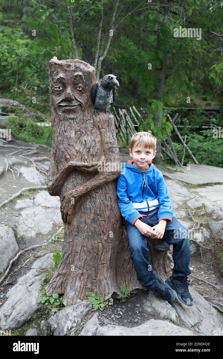 Kid sitting on stump chair in park, Karelia Stock Photo - Alamy