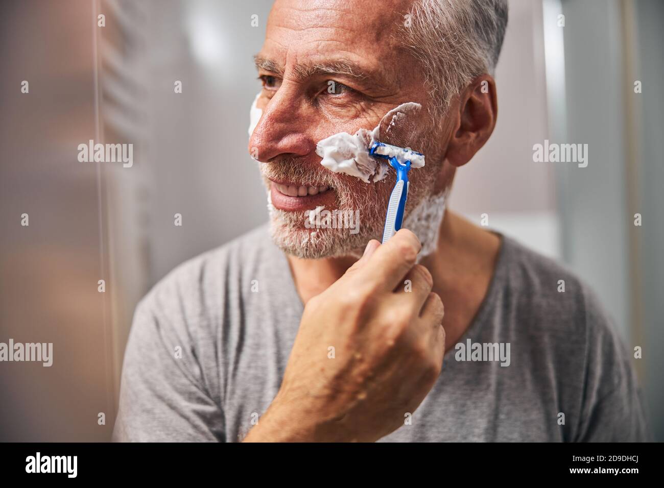 Joyous aged man with a razor doing a shaving procedure Stock Photo - Alamy