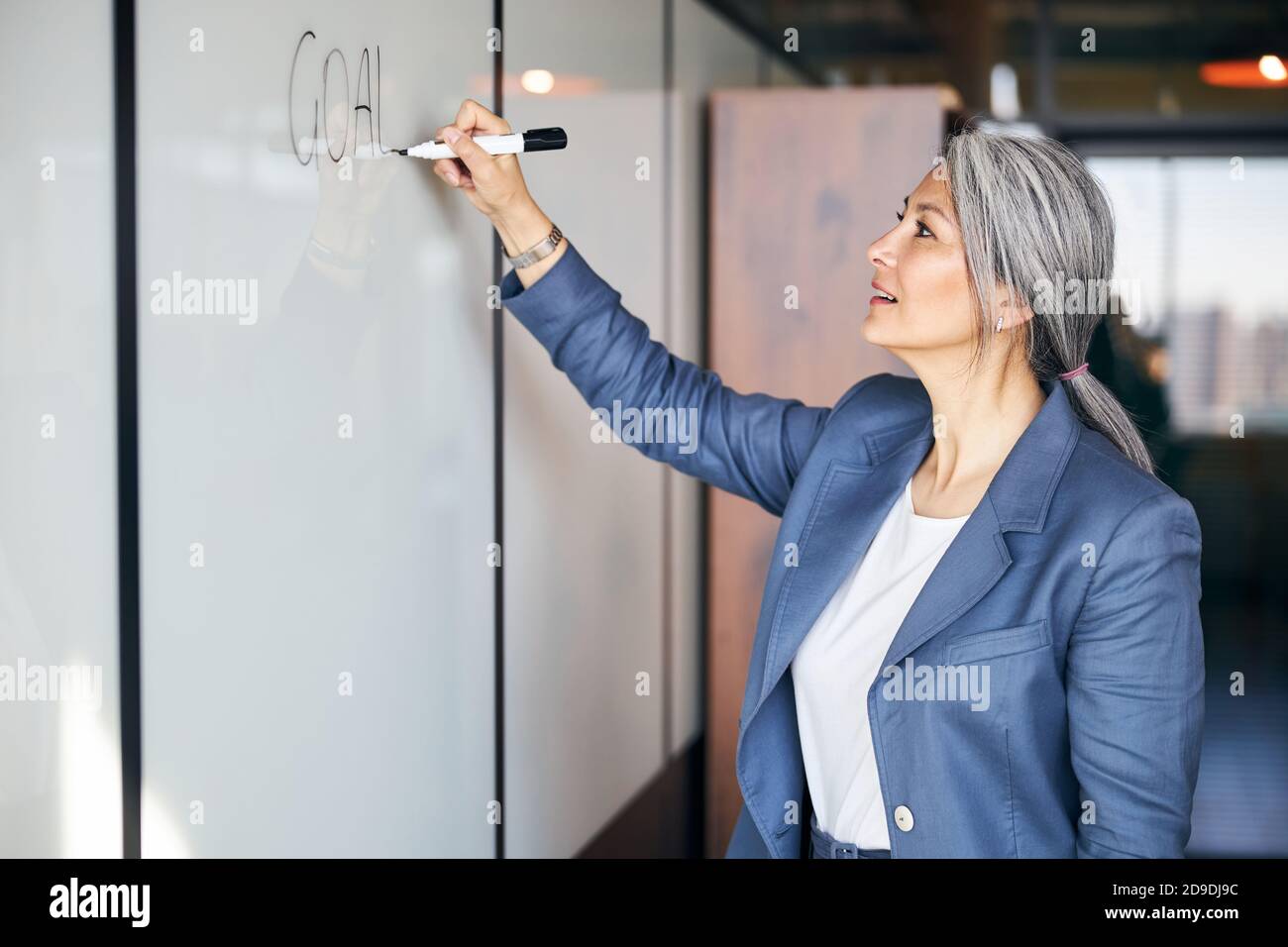 Beautiful woman writing on whiteboard in office Stock Photo - Alamy