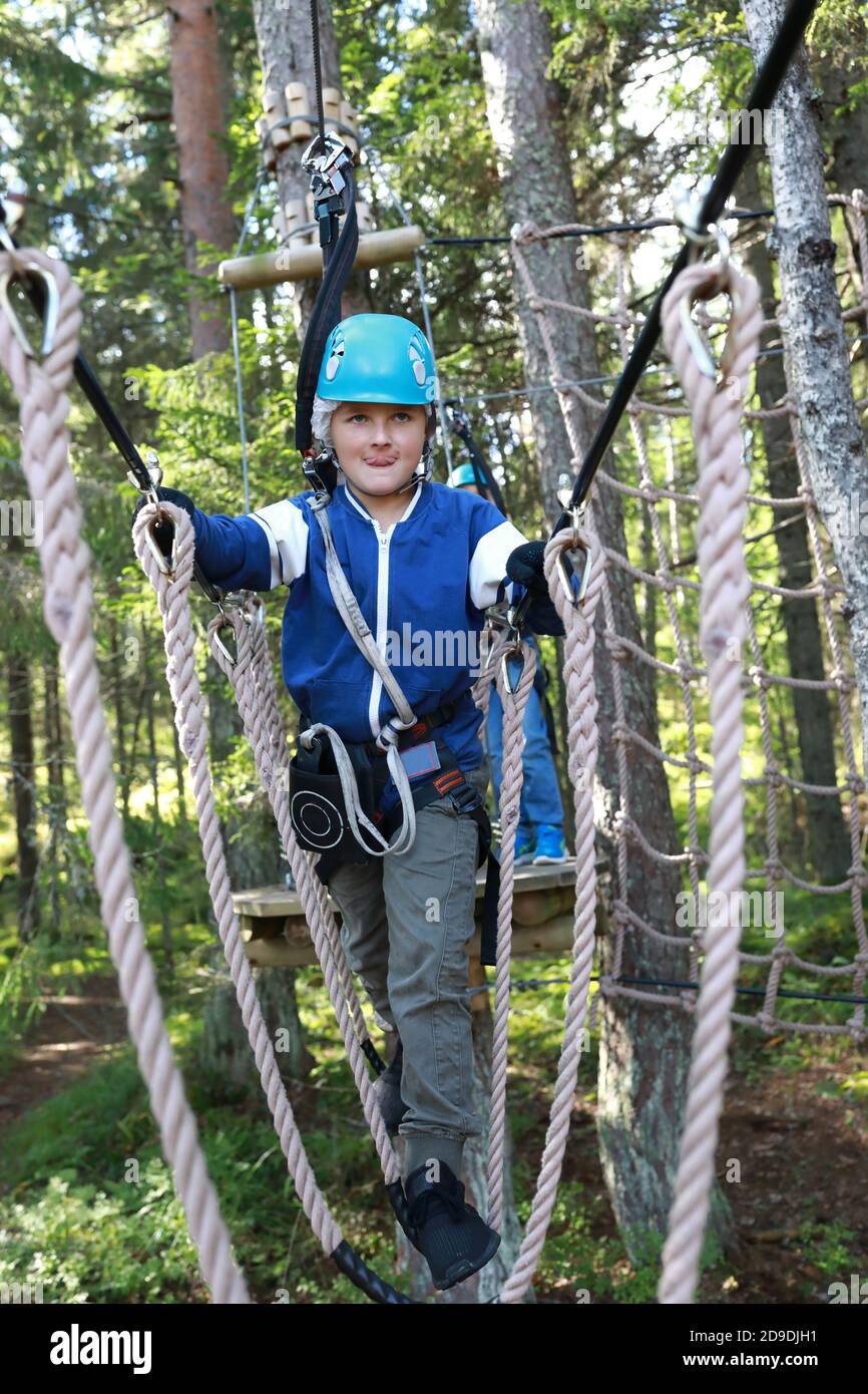 Child overcoming hanging ropes obstacle in forest adventure park ...