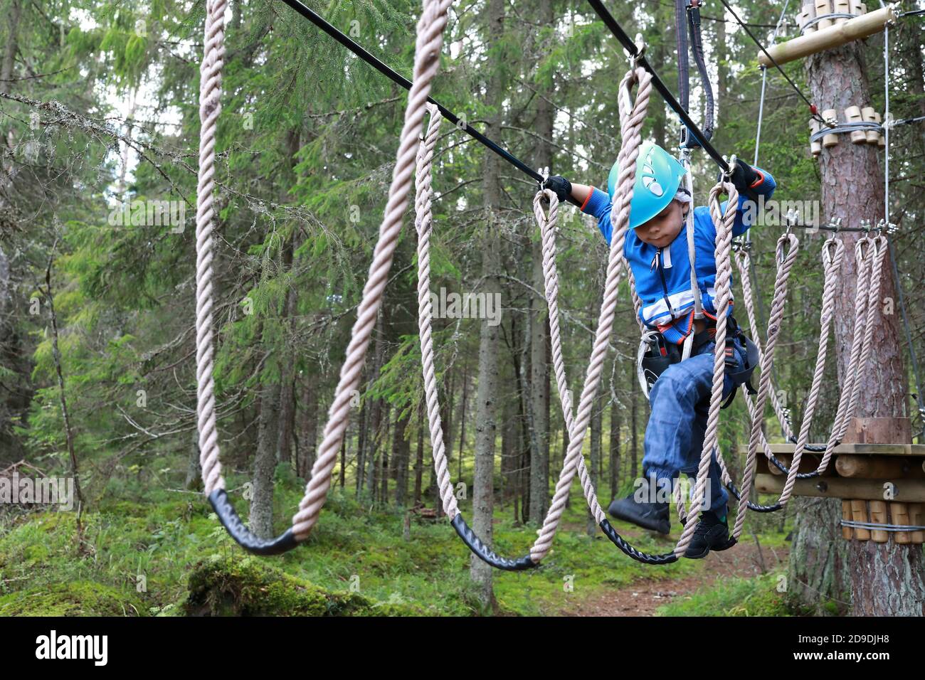 Boy overcoming hanging ropes obstacle in forest, Karelia Stock Photo ...