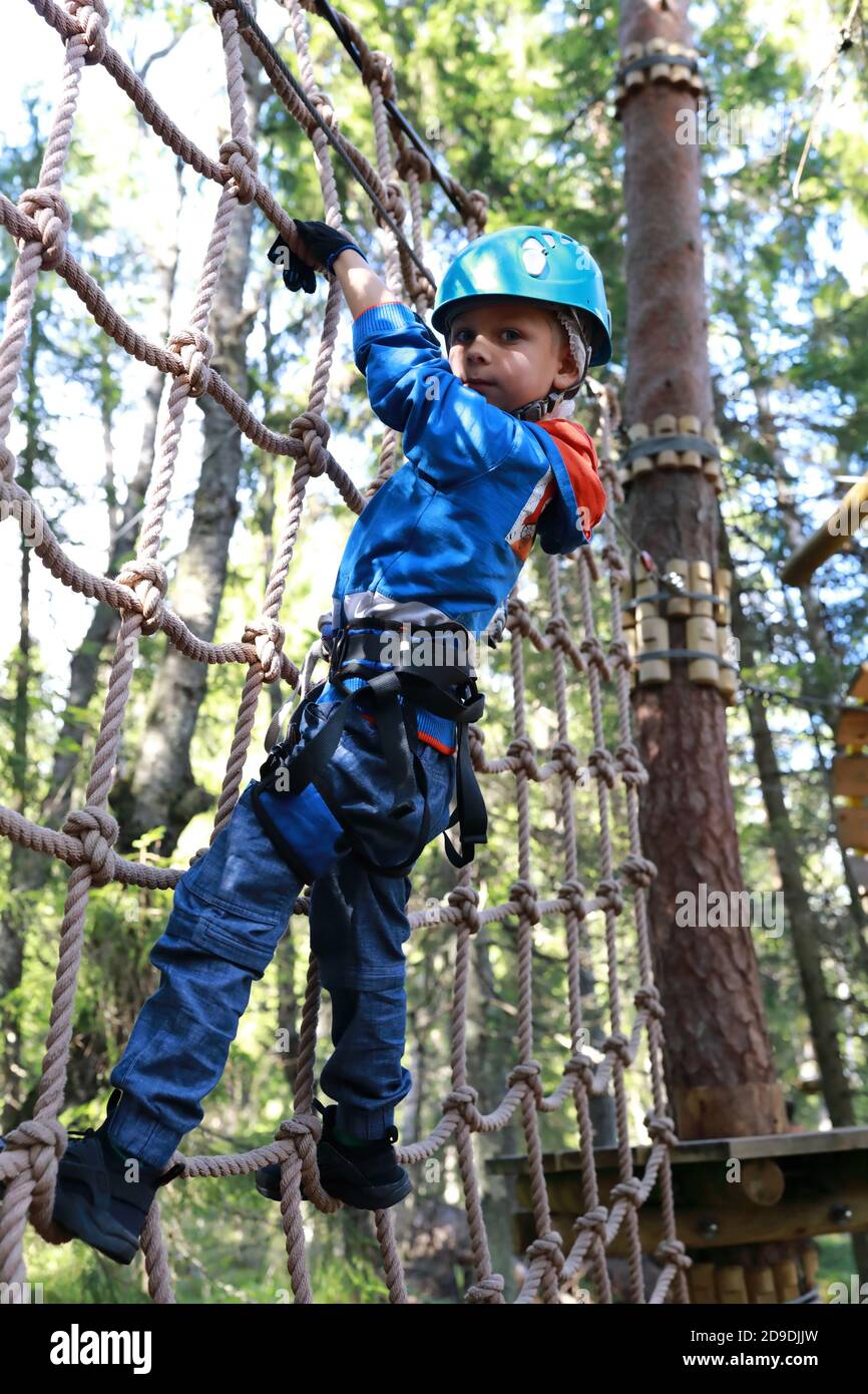 Child overcoming mesh obstacle in forest adventure park, Karelia Stock ...