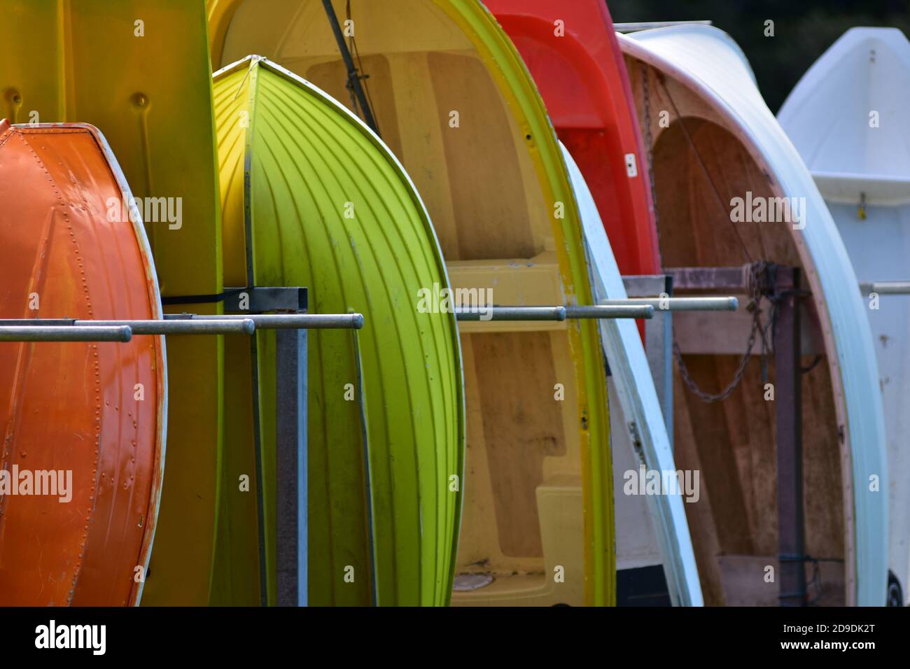 Colourful dinghies of various sizes and materials standing in row in ...