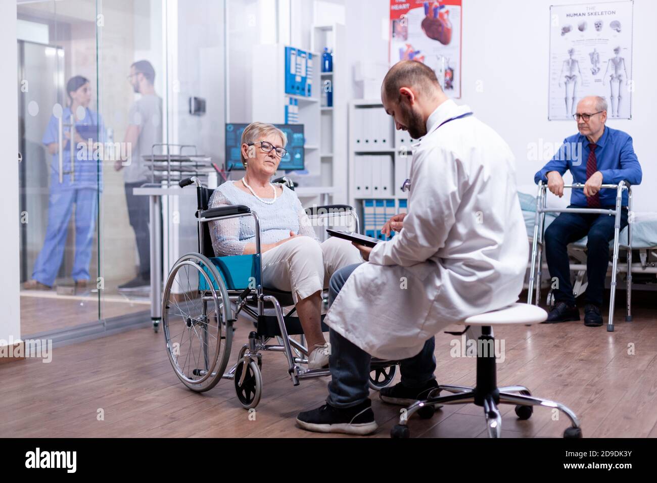 Invalid senior woman sitting in wheelchair in hospital room with doctor ...