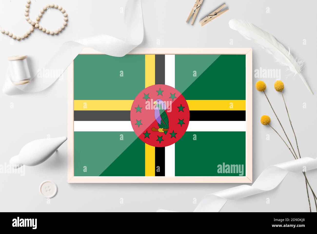 Dominica flag in wooden frame on white creative background. White theme ...