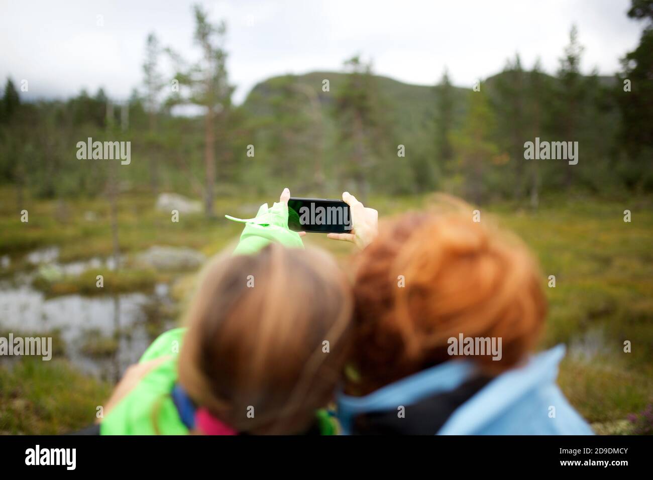 Portrait from behind two people holding camera phone to take selfie in ...