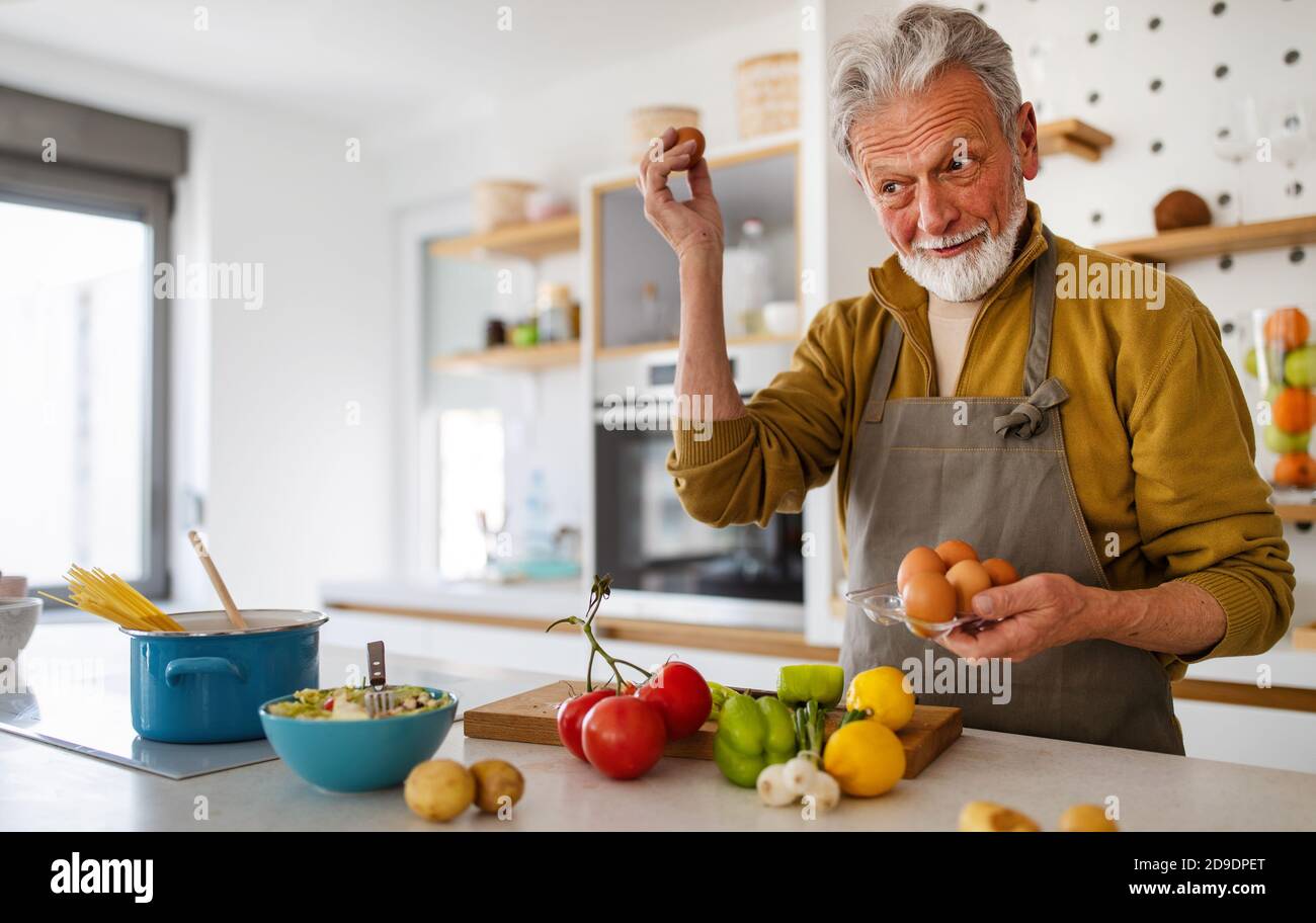 Happy retired senior man cooking in kitchen. Retirement, hobby people ...