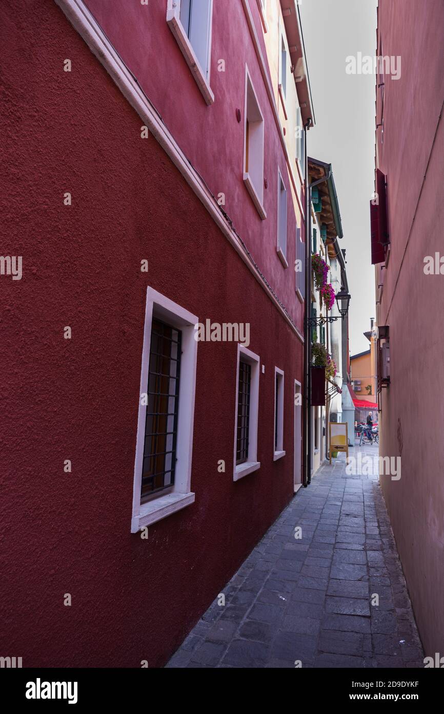 Narrow passage between colorful old buildings in city center. Caorle ...