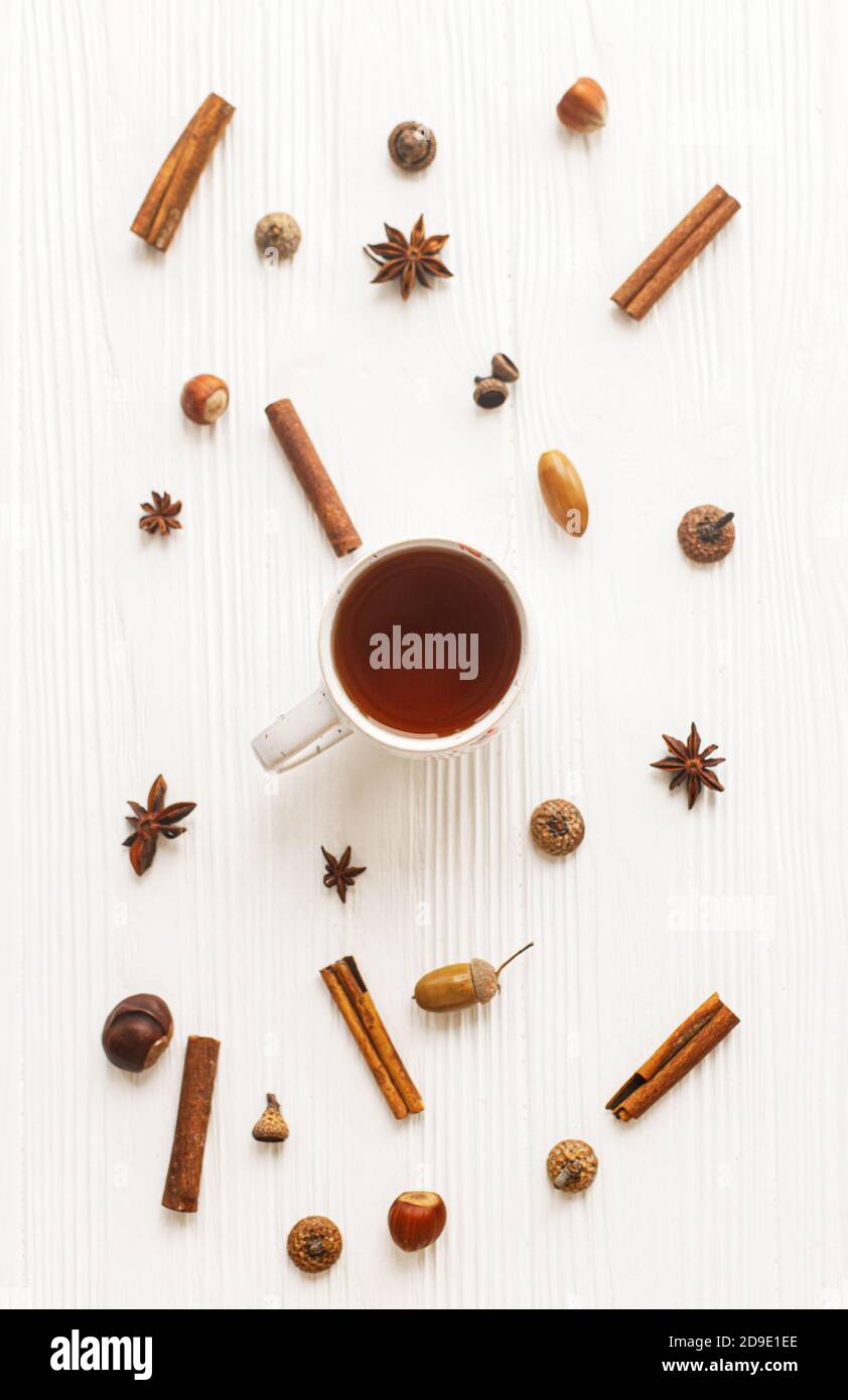 Warm tea in stylish cup, anise star, cinnamon sticks, acorn and nuts on ...