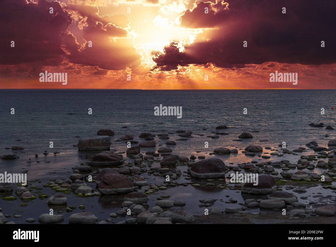 Dramatic red cloudy sunset sky over sea coast with boulders Stock Photo ...