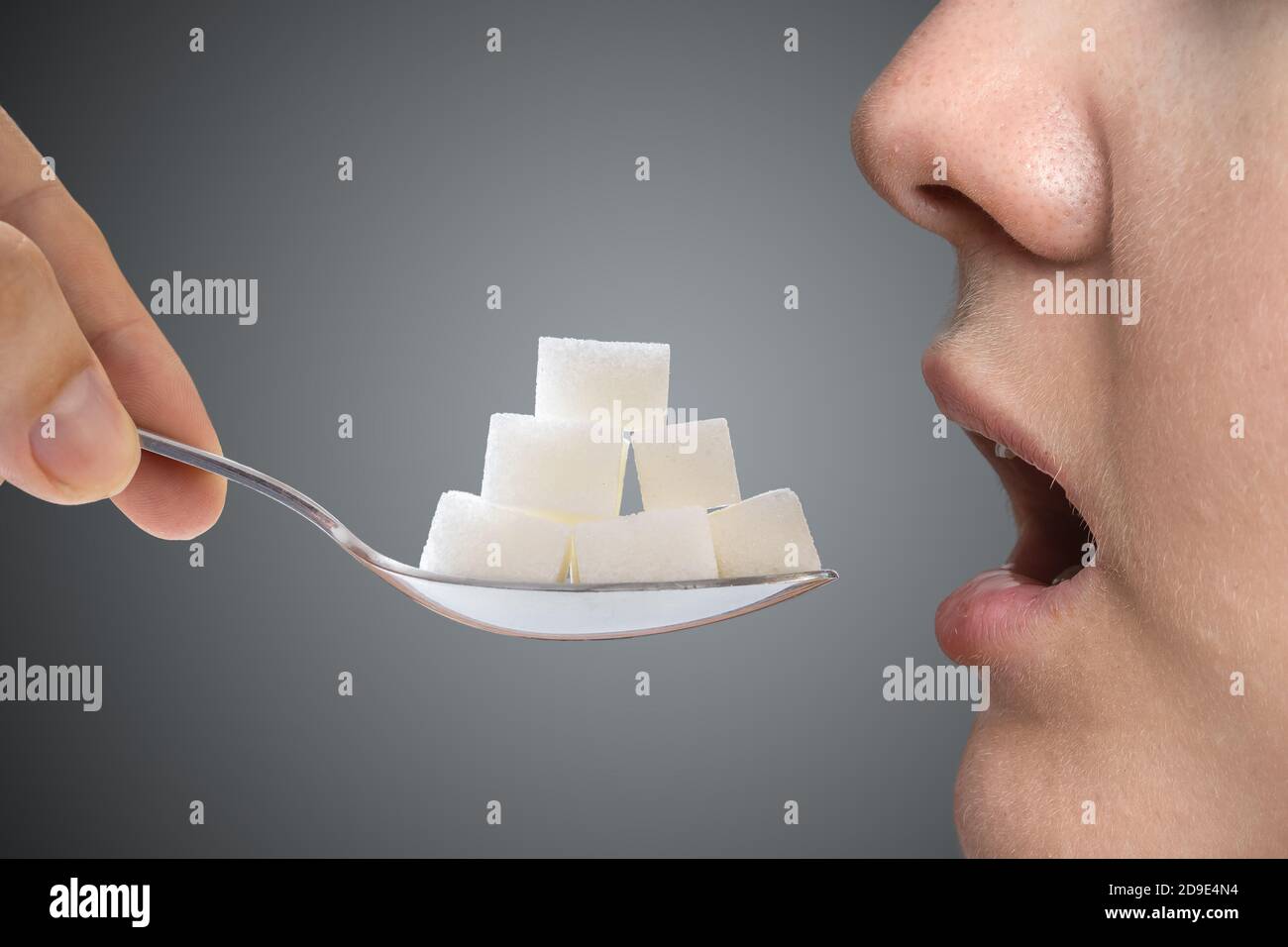 Woman addicted on sugar is eating spoon full of sugar blocks. Unhealthy ...