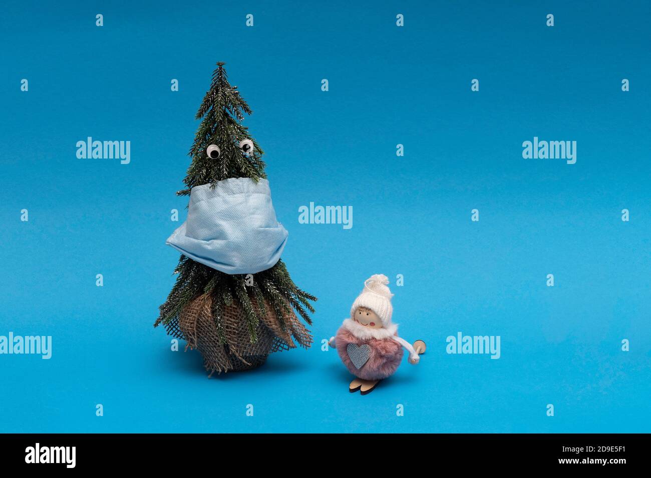Christmas tree with facial mask and googly eyes, toy girl on blue ...