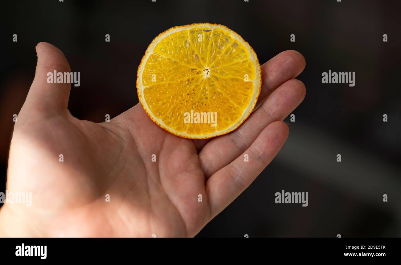 Sliced circle of orange in the palm. Cooking orange decor and chips ...