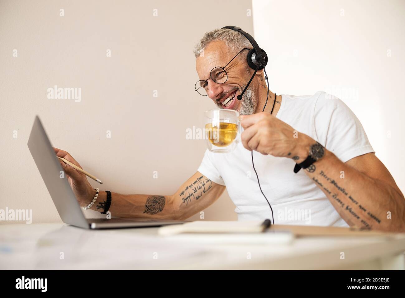 Worker with tattooed arms drinking tea and touching the screen Stock ...