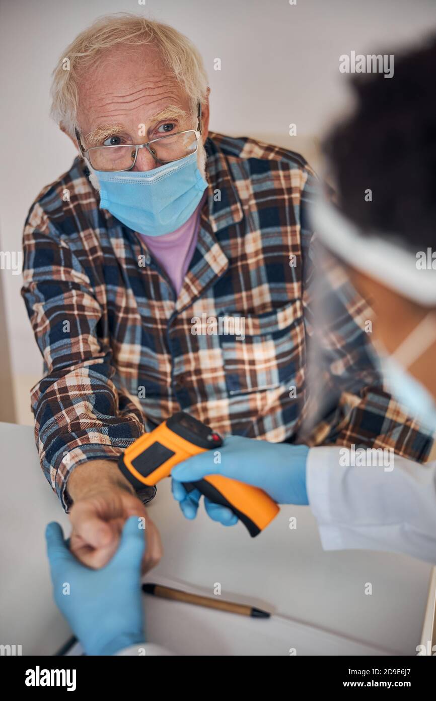 Geriatric physician using a non-contact infrared thermometer Stock ...