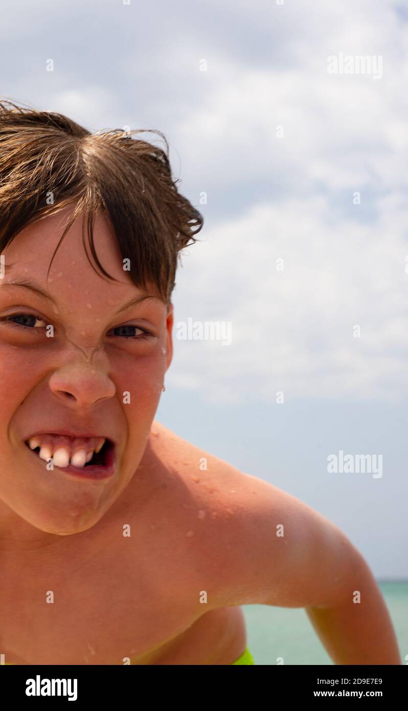 The boy in emotions against the blue sky. Close-up. White-toothed smile ...