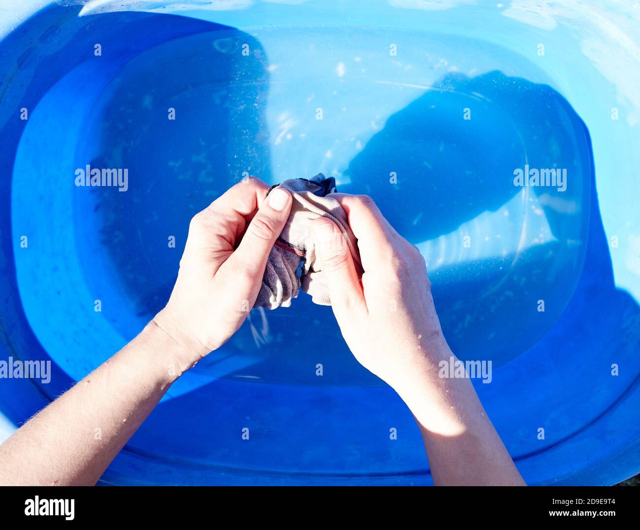 Manual hand washing. Close-up of woman hand washing laundry in blue ...