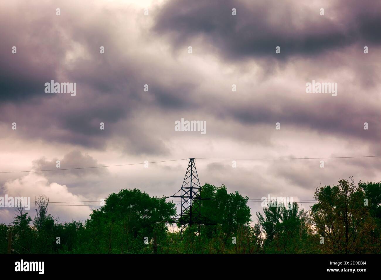 Beautiful cloudy sky over transformer line tower and green treetops ...