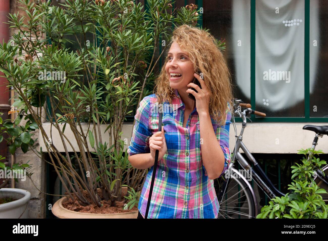 Portrait happy woman standing outside talking with mobile phone Stock ...
