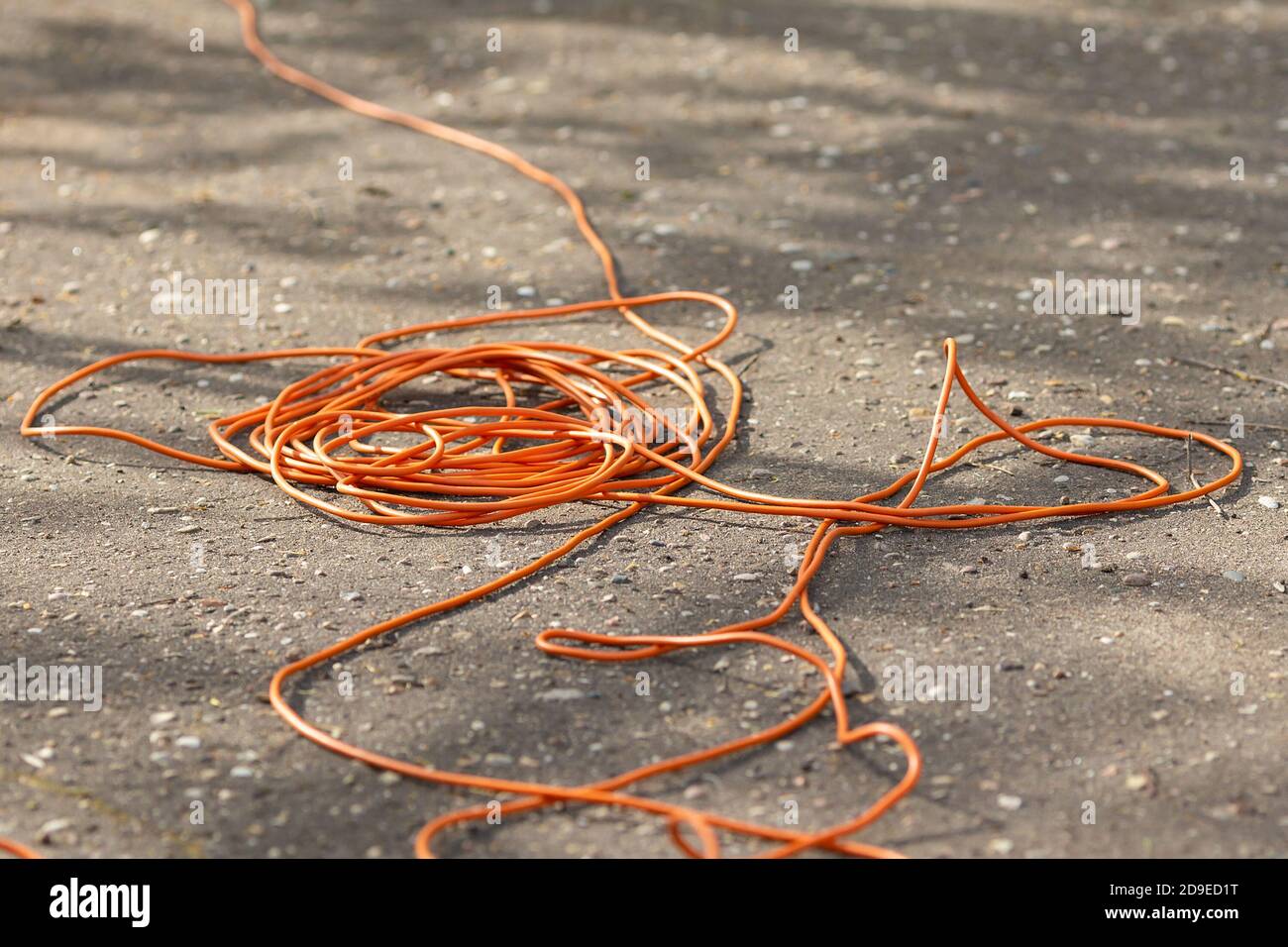 An orange long electric wire lies on the asphalt Stock Photo - Alamy