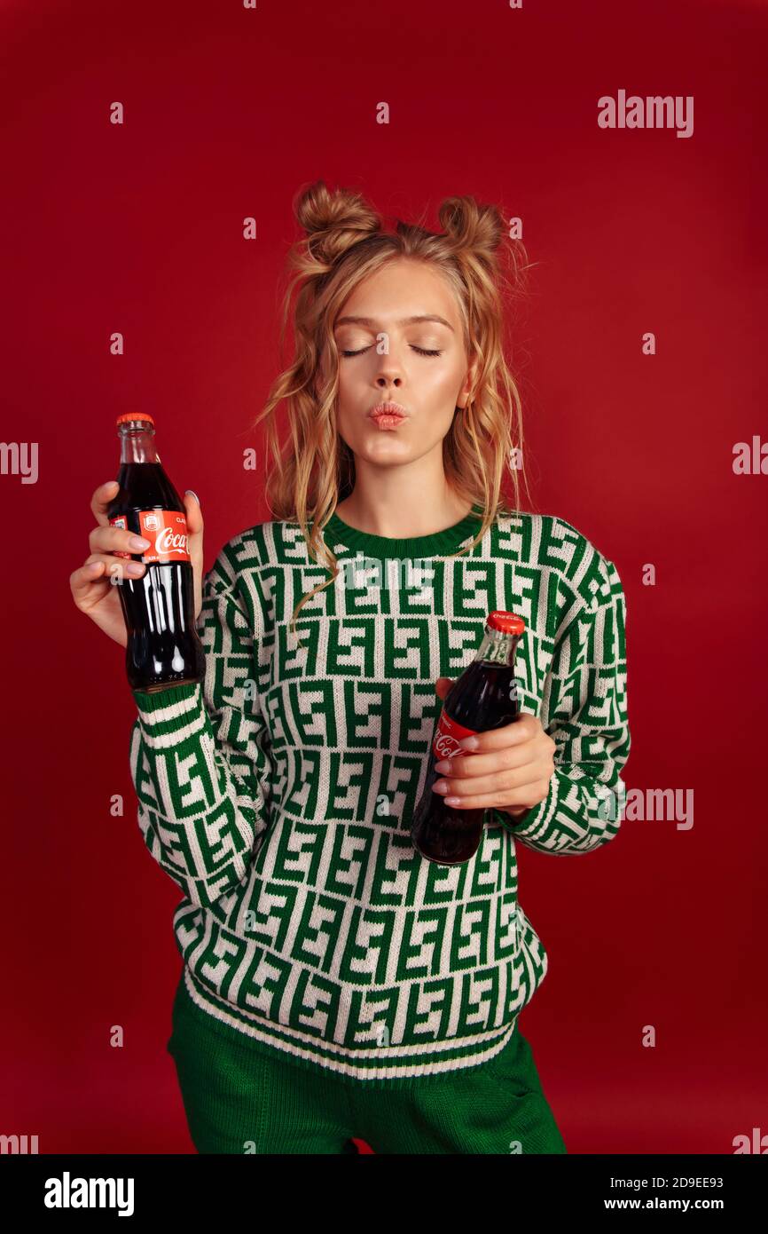 Pretty young girl keeps her eyes closed holds two bottles of coke ...