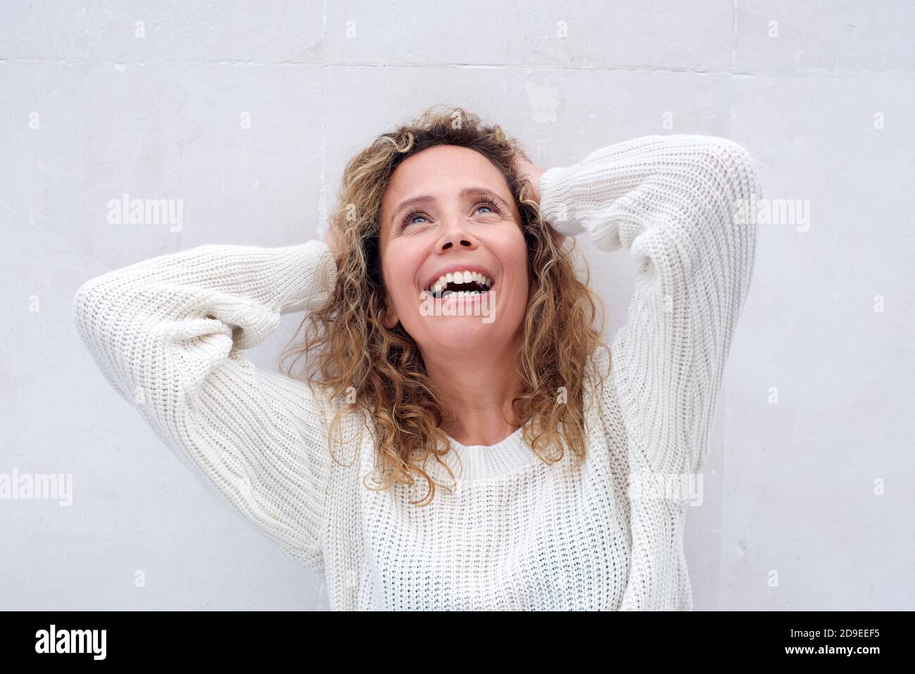 Close up portrait beautiful older woman laughing with hand behind head against white background ...
