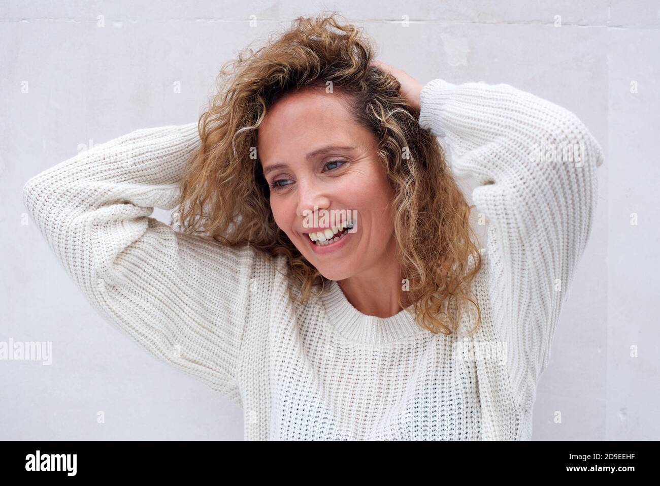 Close up portrait beautiful older woman laughing with hands behind head against white background ...