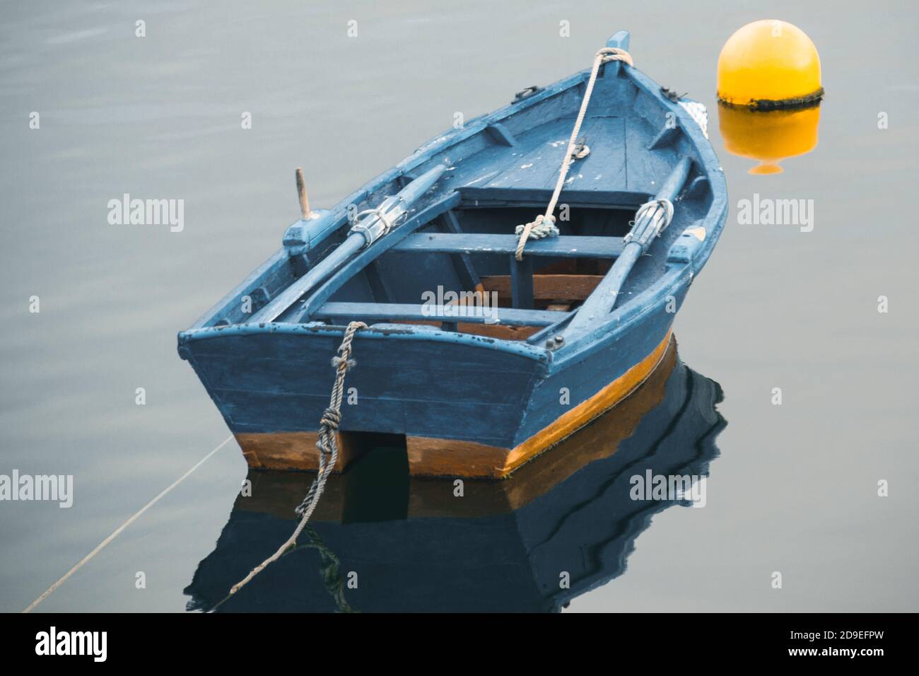 Small blue fishing boat in front of a yellow buoy on a calm sea Stock ...